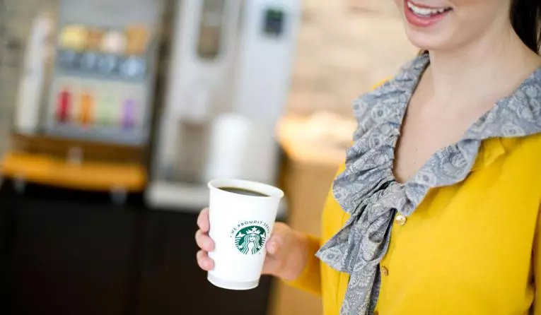 Ein Kunde hält eine Starbucks-Tasse Kaffee in der Hand.