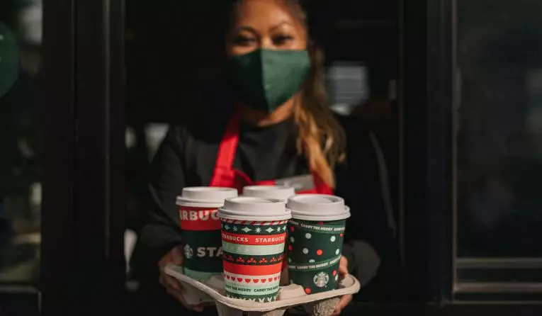 Starbucks-oficisto tenante feriajn tasojn.