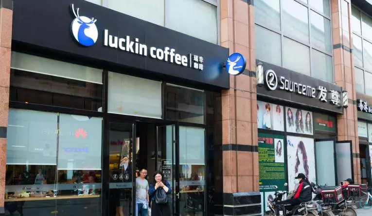 Blick auf die Straße von Chinesen, die einen Luckin Coffee Shop in Wuhan China verlassen.
