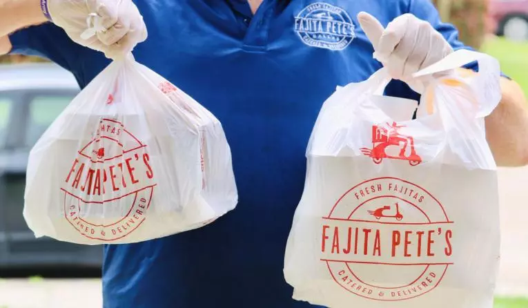 Fajita Petes To-Go-Bestellungen in Tüten, die von einem Mitarbeiter getragen werden.