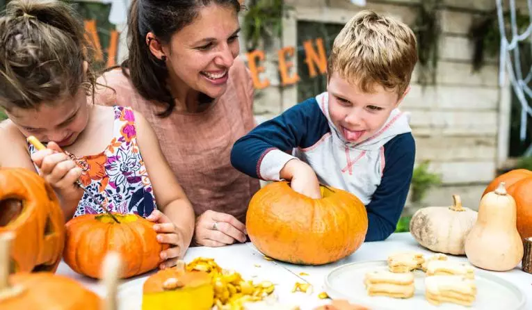 Un genitore intaglia la zucca con i suoi figli.