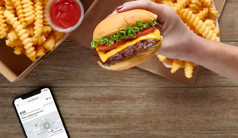 Shake Shack burger nyob rau hauv pem hauv ntej ntawm ib lub xov tooj nrog lub app qhib.