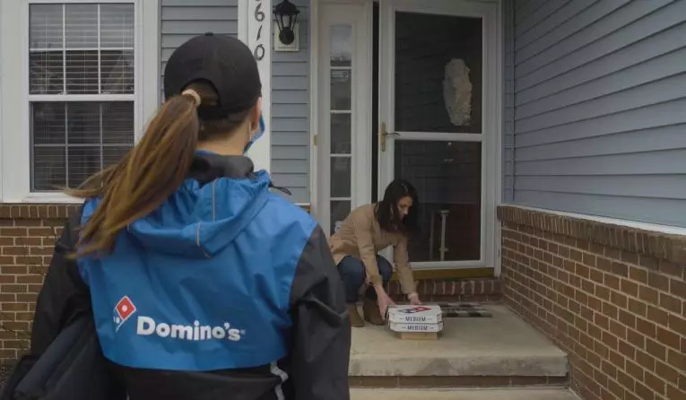 El repartidor de Domino deixa una pizza.
