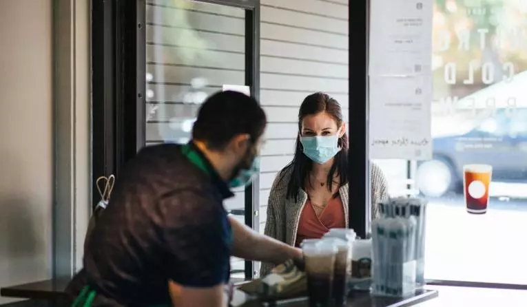 Il cliente di Starbucks che indossa una maschera prende un drink.