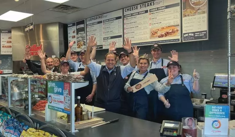 Вработените и извршниот директор на Jersey Mike's Subs слават во ресторанот.