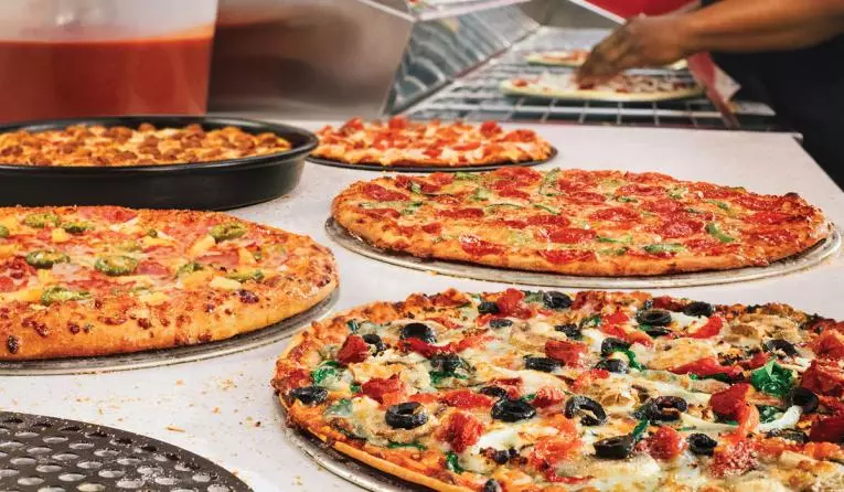 Lima pizza Domino di atas meja.