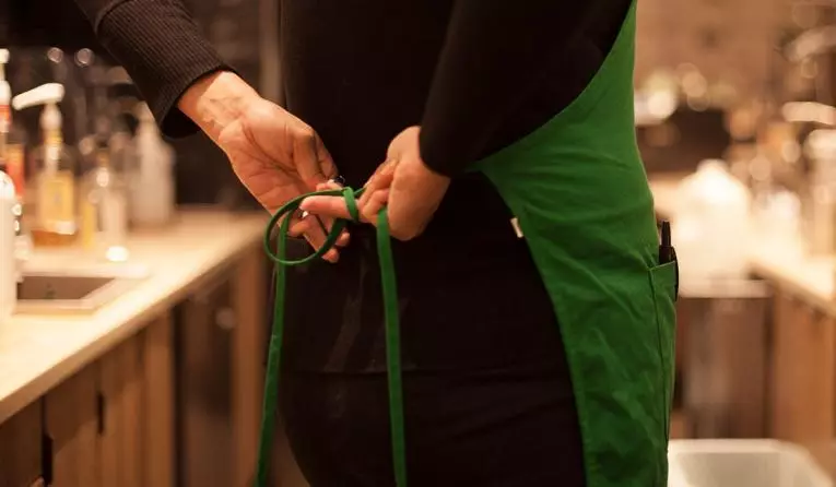 Zaposlenik Starbucksa veže pregaču.