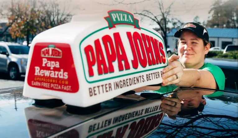 Ang naghatod nga driver ni Papa John duol sa usa ka sakyanan.