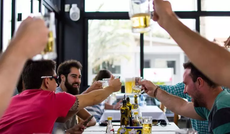 Les clients du restaurant applaudissent à une table avec des bières.