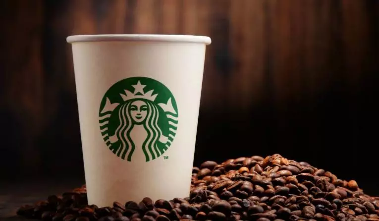 Starbucks-ის ფინჯანი და ყავის მარცვლები.