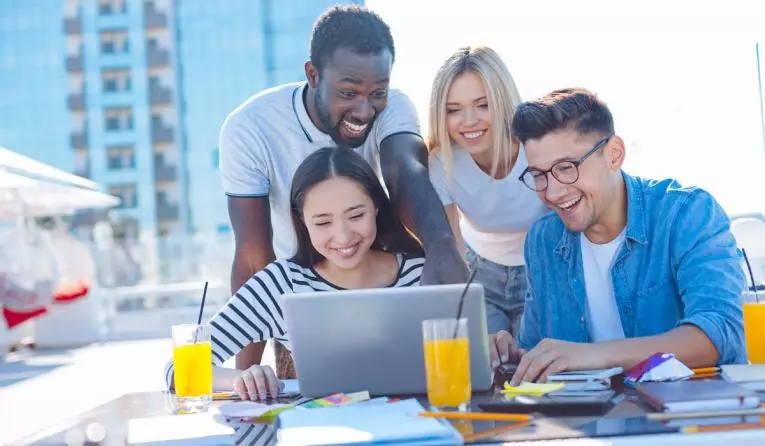 Studentë të adhurueshëm duke buzëqeshur ndërsa punojnë së bashku në projekt.