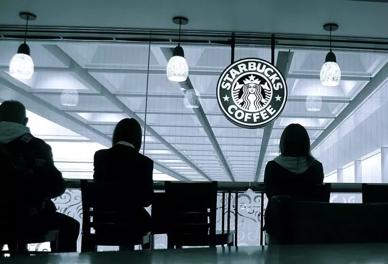Starbucks'ta kahve içerken konuklar pencereden dışarı bakıyor.