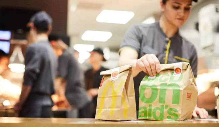 Um funcionário do McDonald's coloca dois sacos de comida em um balcão.