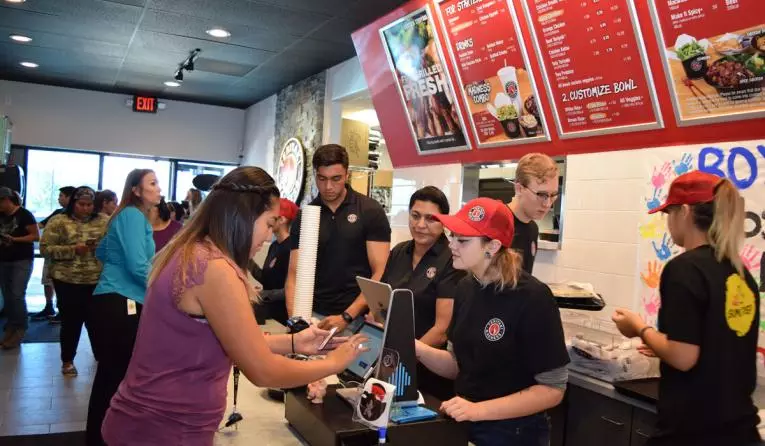 Usa ka kustomer nag-order og pagkaon gikan sa usa ka cashier sa Teriyaki Madness restaurant.