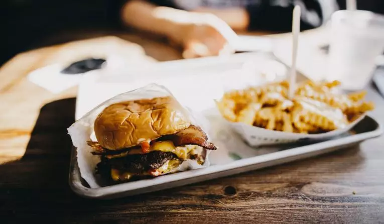 Burger og pommes frites på et brett.